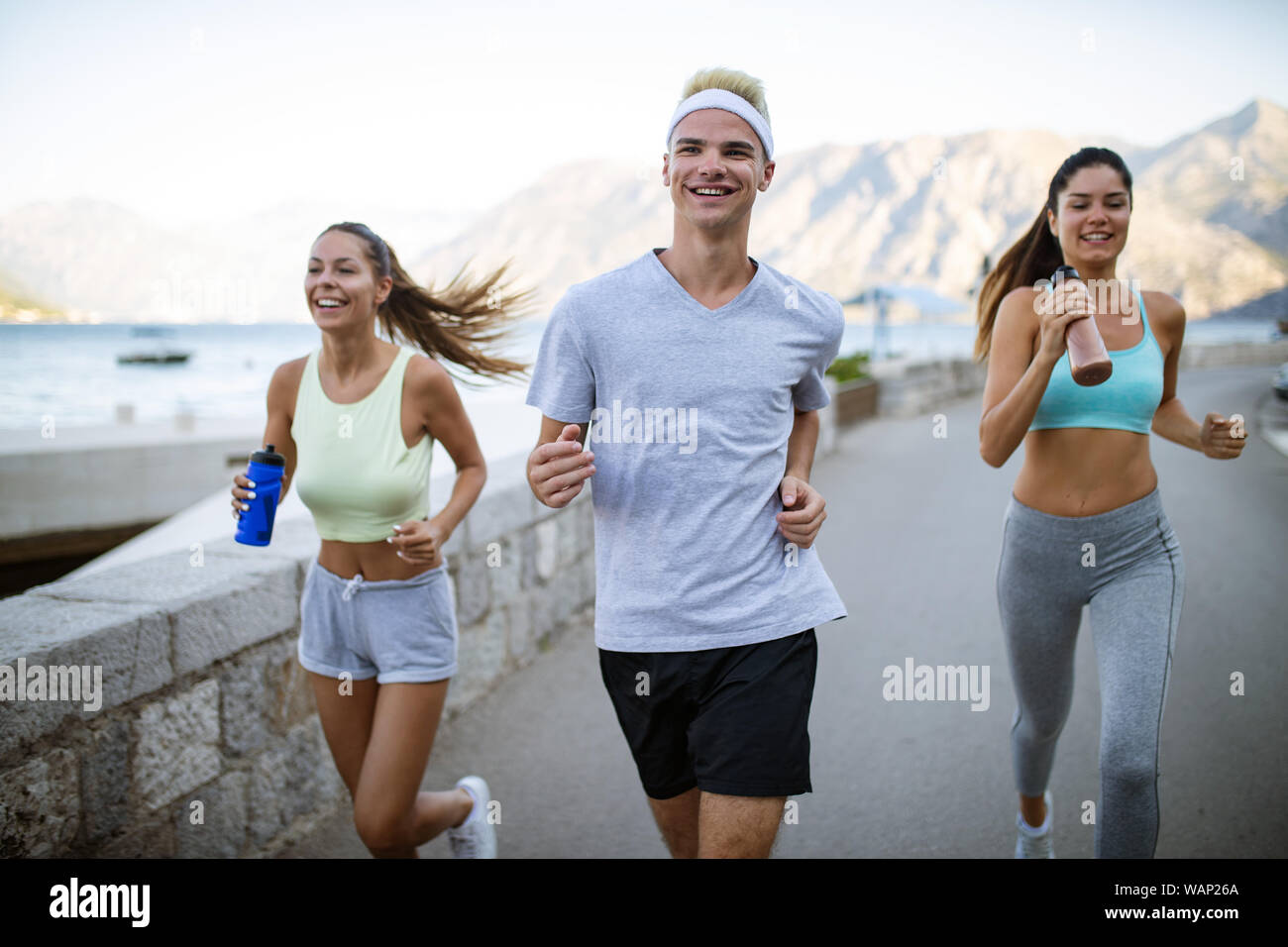 Happy fit people running and jogging together in summer sunny nature ...
