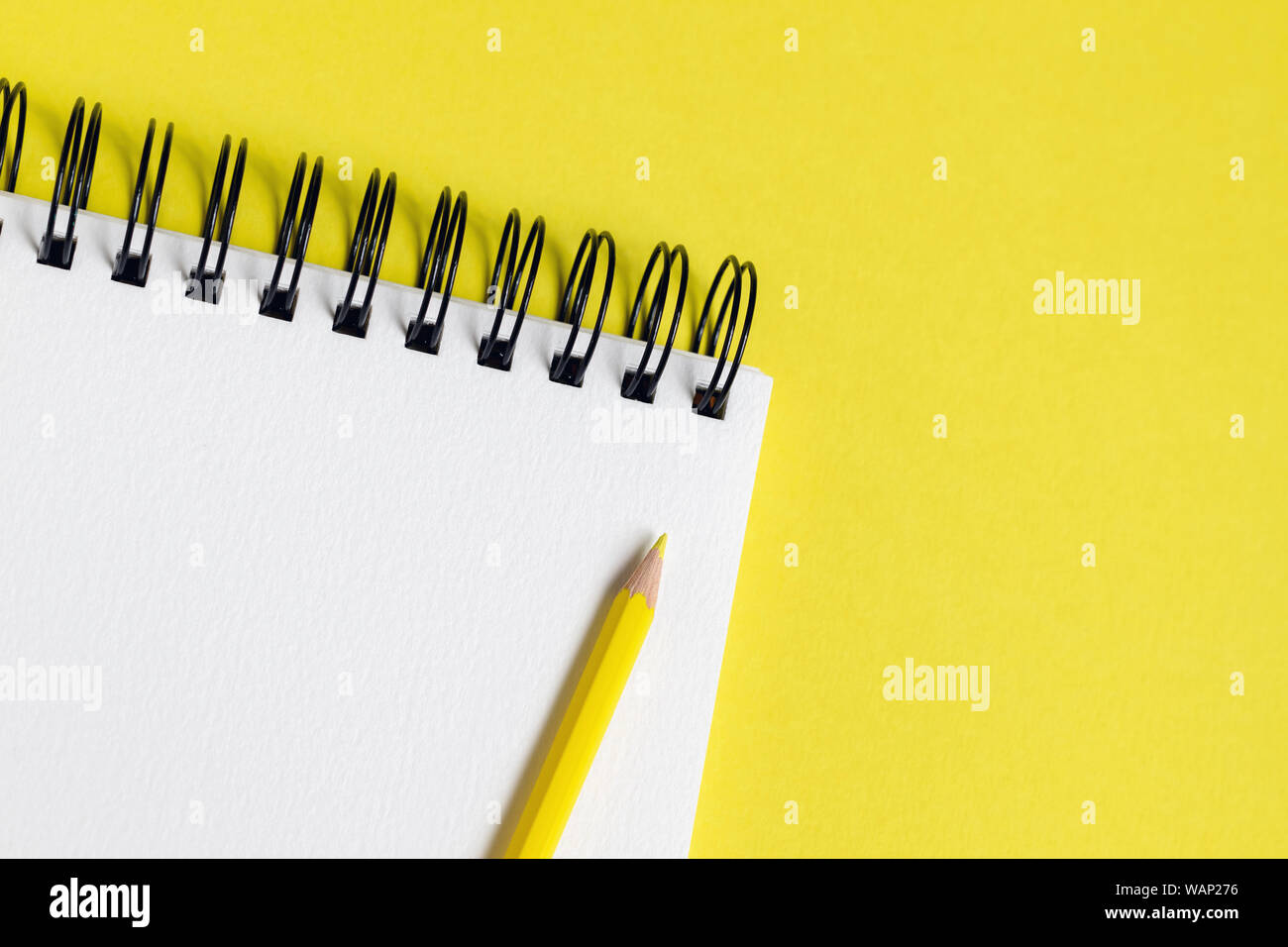 Corner of a spiral bound notepad / sketchpad on a yellow background ...