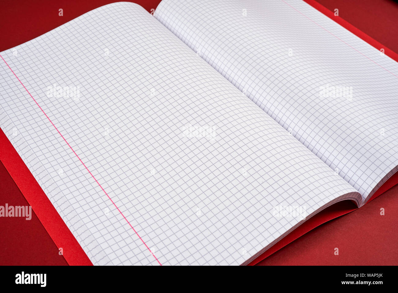 open notebook with checkered pages on a red background Stock Photo - Alamy