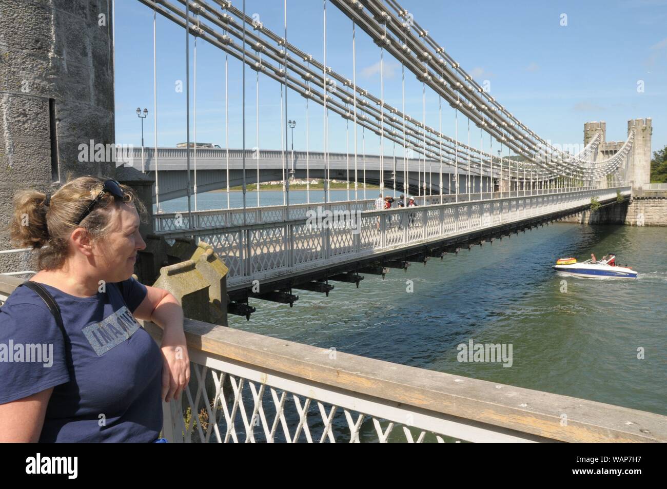 A woman looks across the Conwy Suspension Bridge, Conwy, North Wales ...