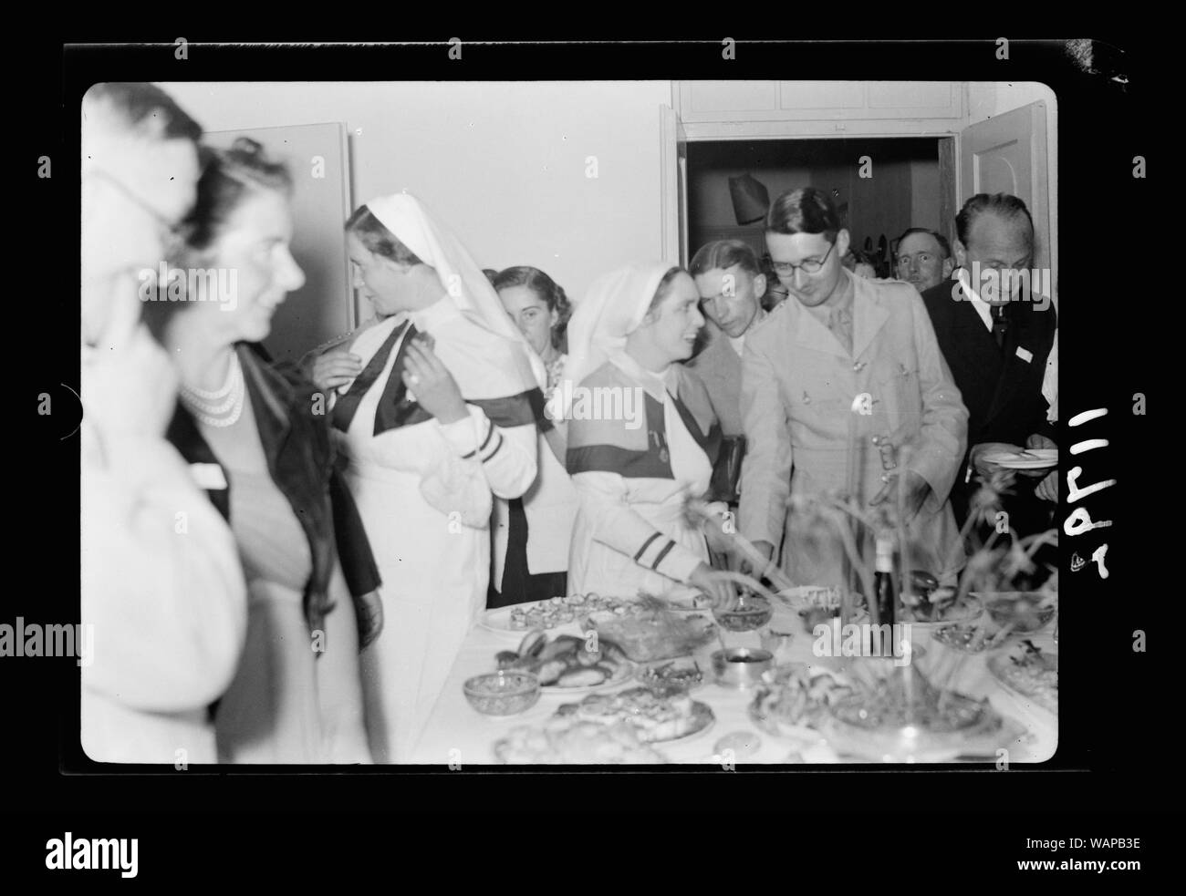 Dance in Dr. & Mrs. Wren's house. Nurses & other guests around buffet ...