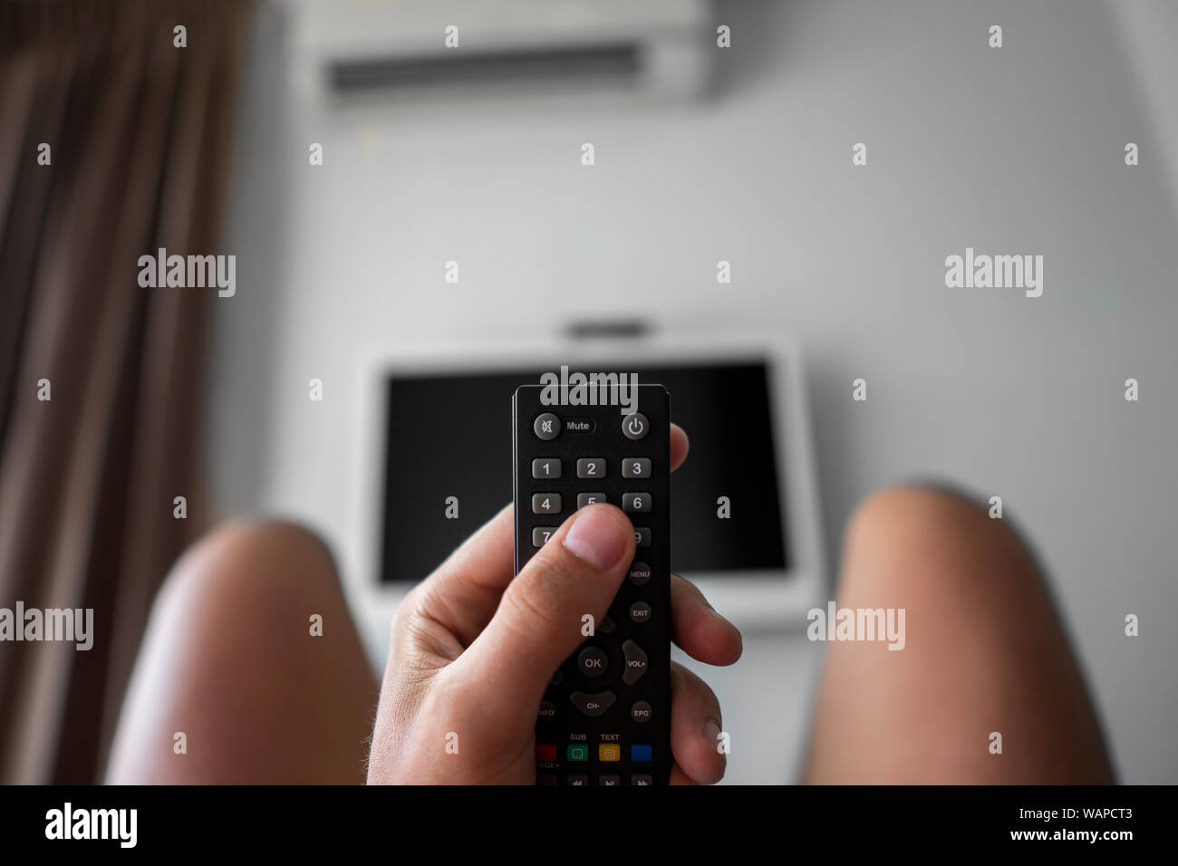 The man with the remote control in hand want switch on the TV and ...