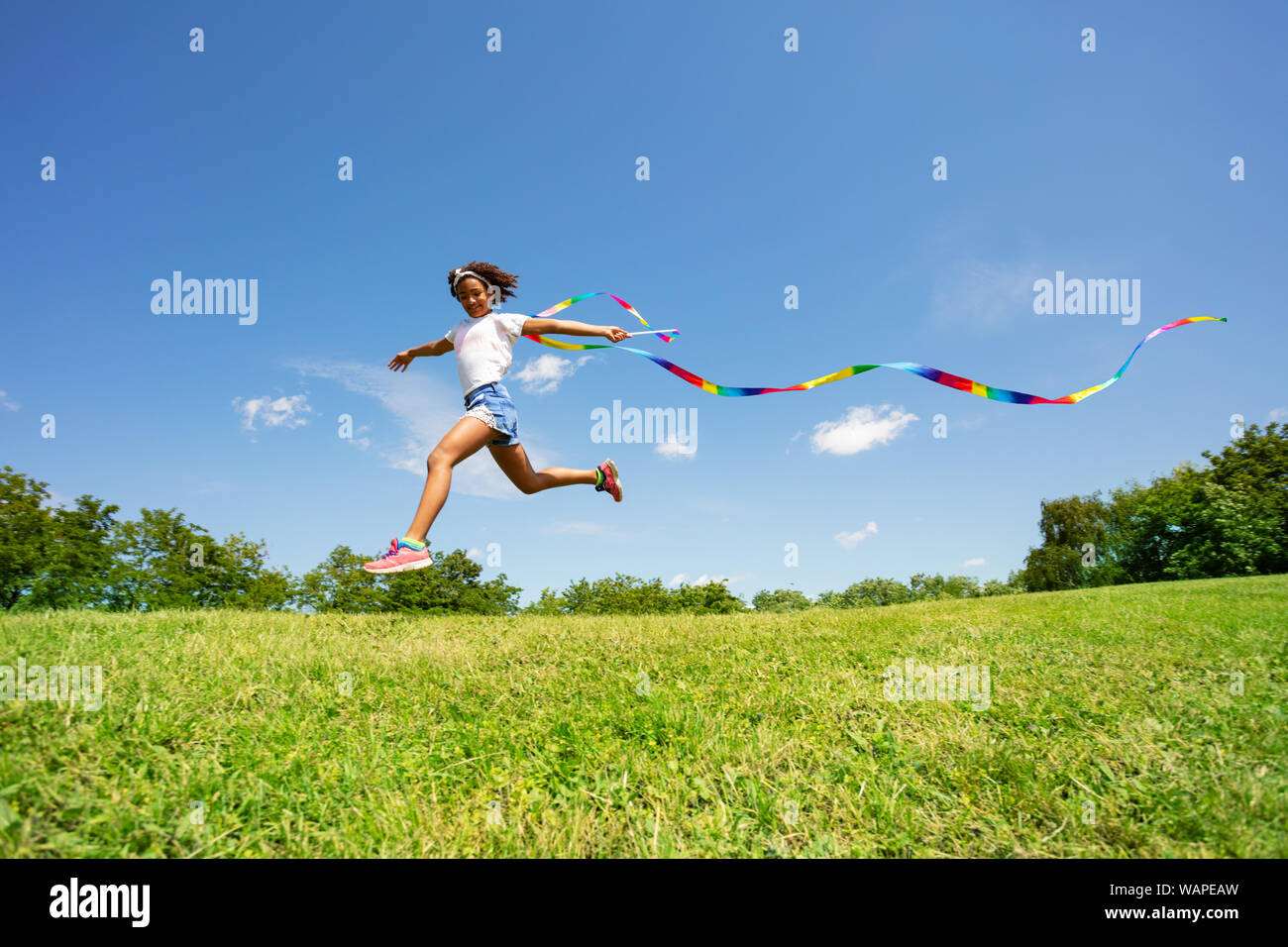 Beautiful young girl jump waving with ribbon Stock Photo - Alamy
