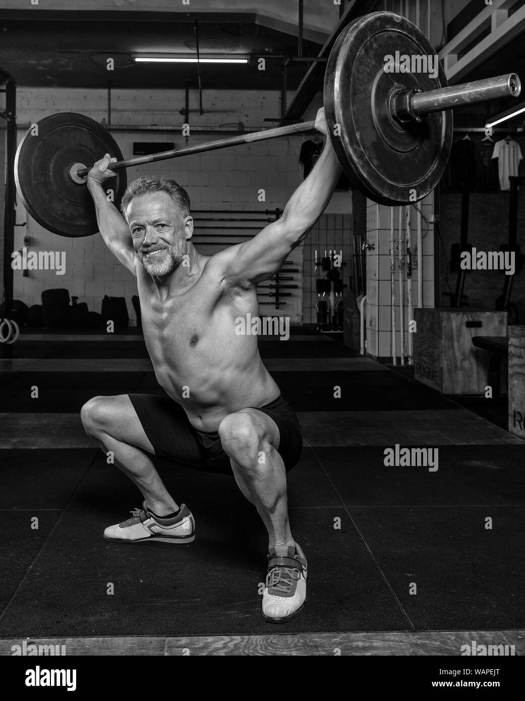 An handsome middle aged male athlete with Sixpack is doing overhead ...