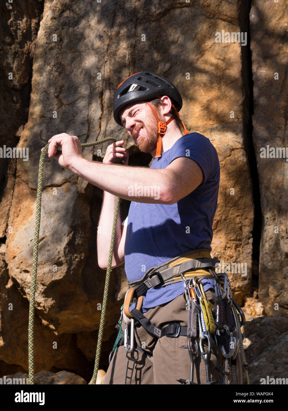 Technical climbing instructor inspecting rope by holding up to eye and ...