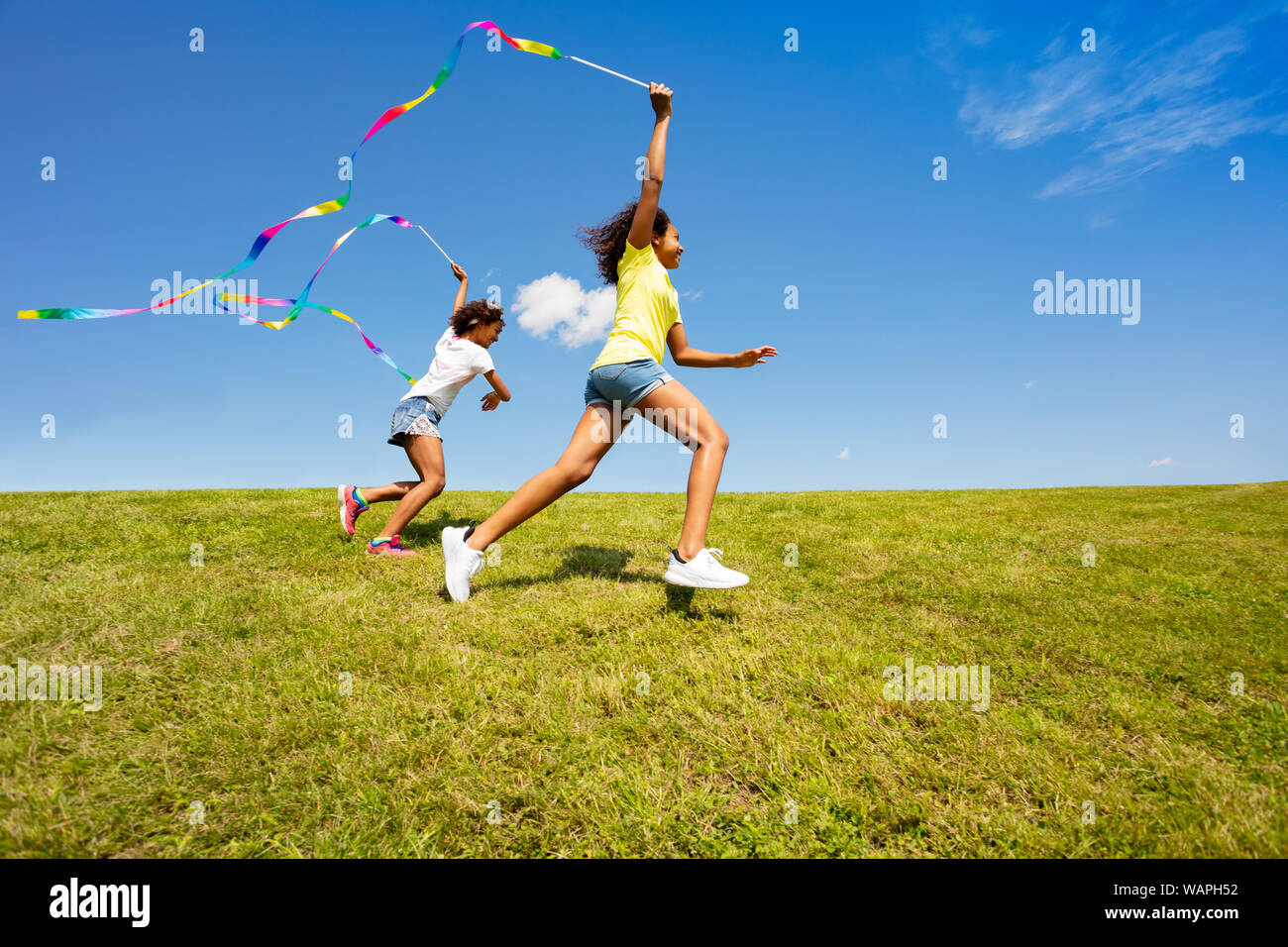 Girls run with ribbon over grass, sky background Stock Photo - Alamy