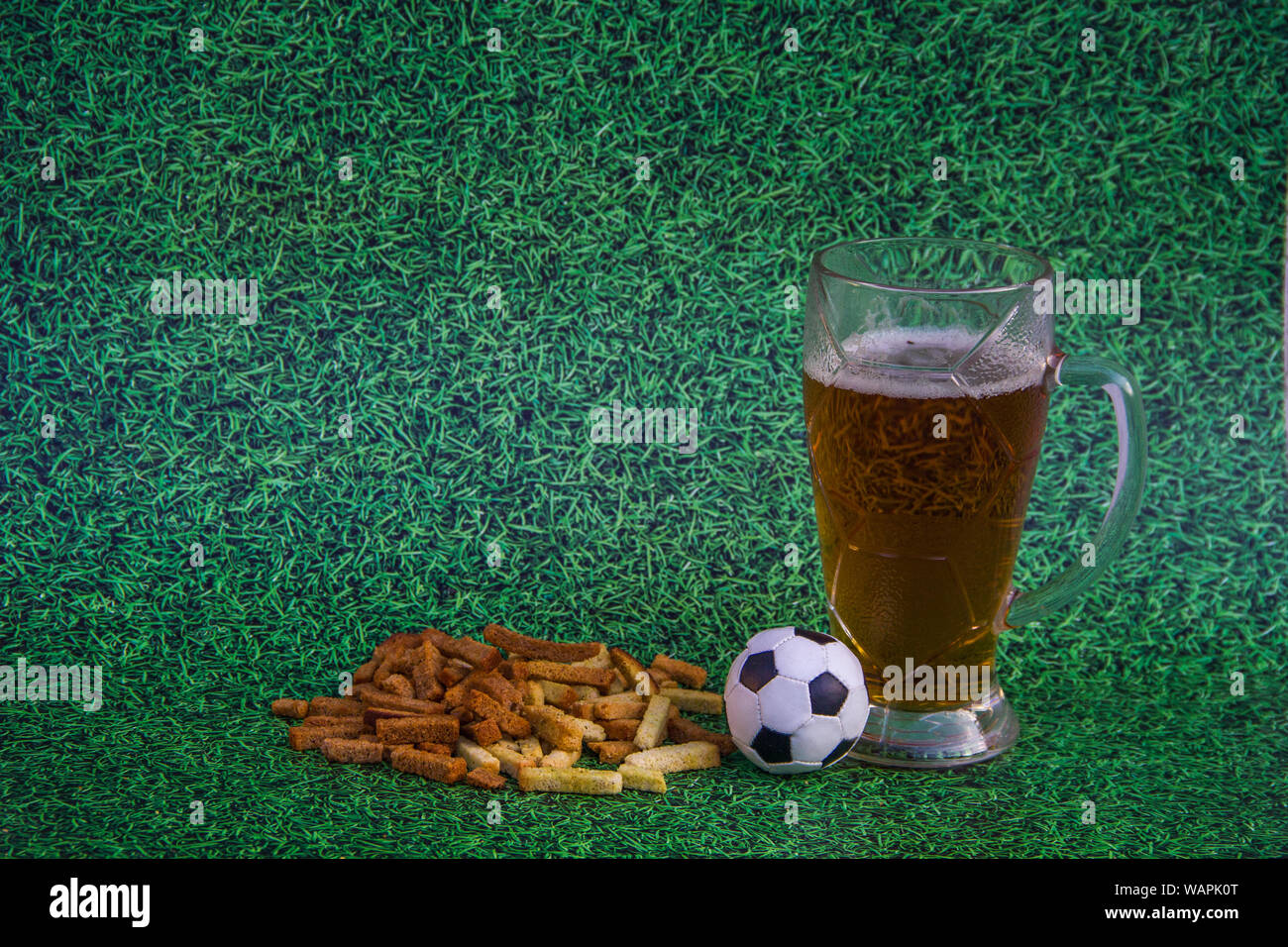 beer glass with beer, crackers, soccer ball on a background of green ...
