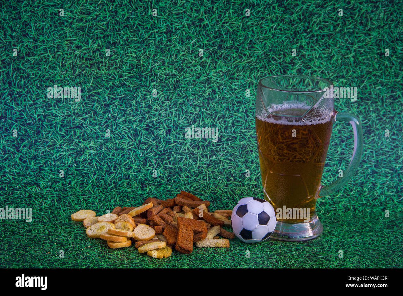 beer glass with beer, crackers, soccer ball on a background of green ...