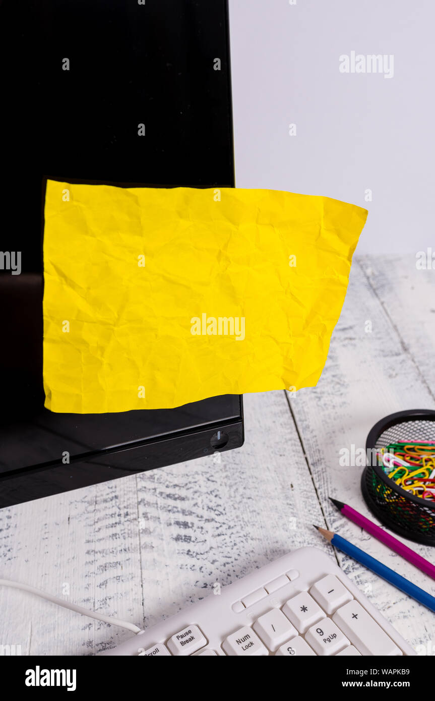 Note paper taped to black computer screen near keyboard and stationary ...