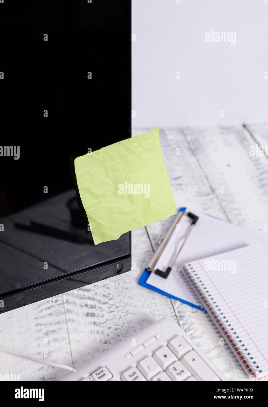 Note paper taped to black computer screen near keyboard and stationary ...