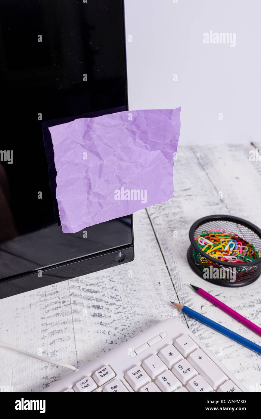 Note paper taped to black computer screen near keyboard and stationary ...