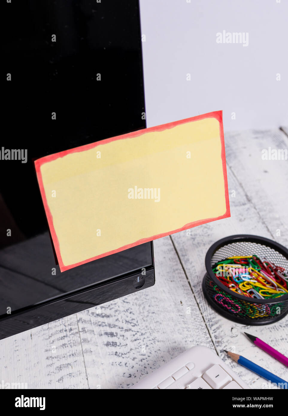 Note paper taped to black computer screen near keyboard and stationary ...