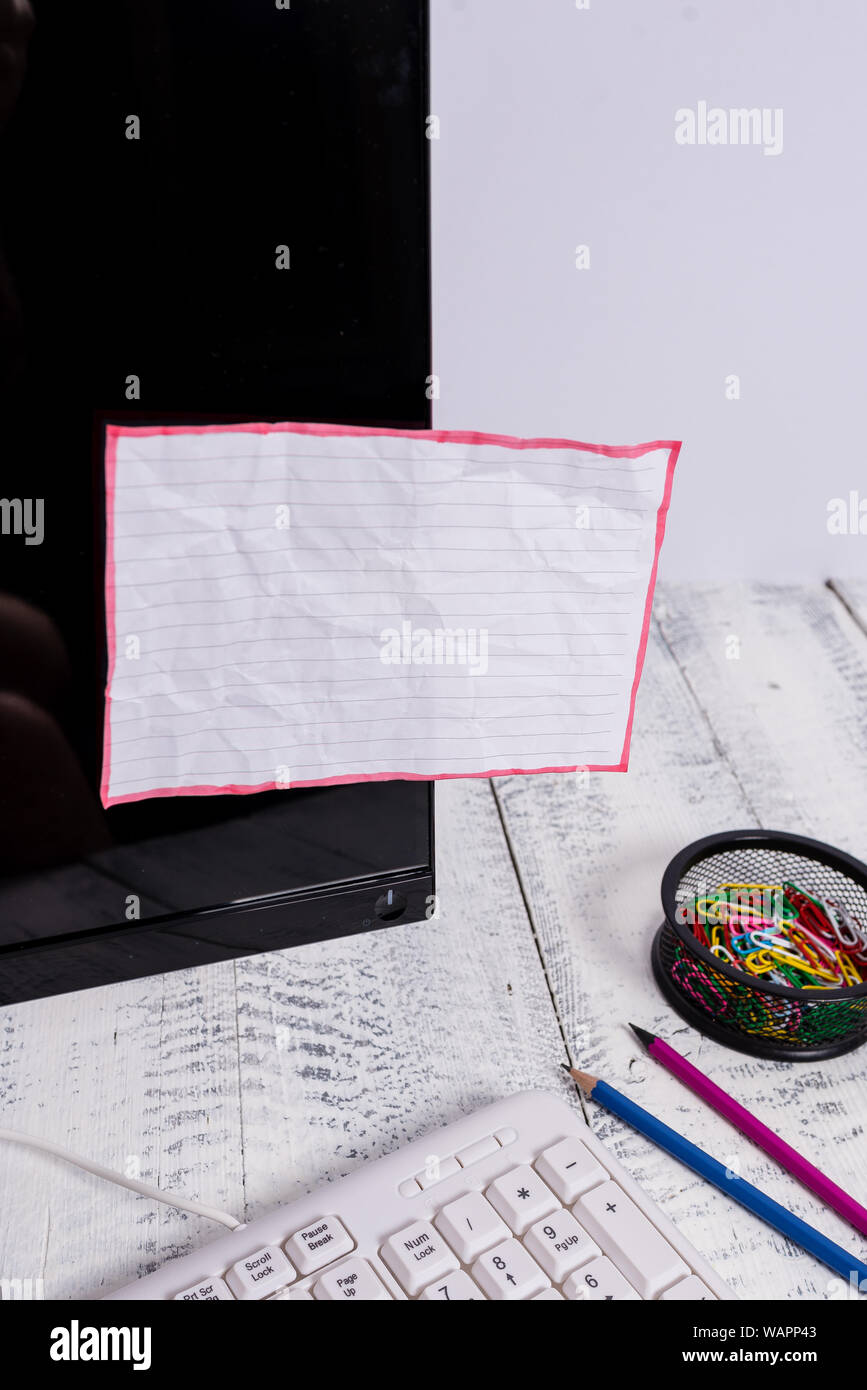 Note paper taped to black computer screen near keyboard and stationary ...