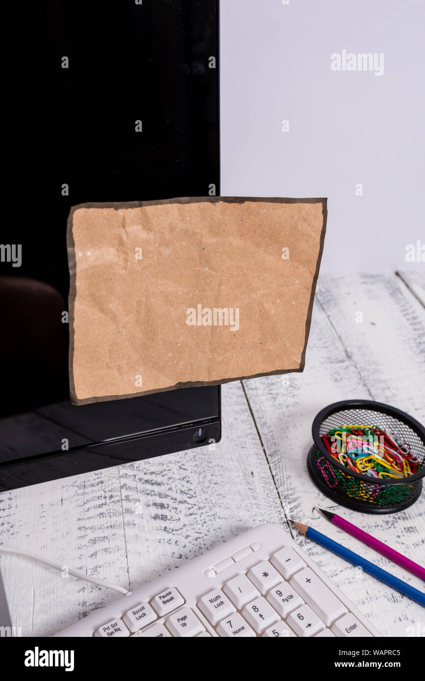 Note paper taped to black computer screen near keyboard and stationary ...