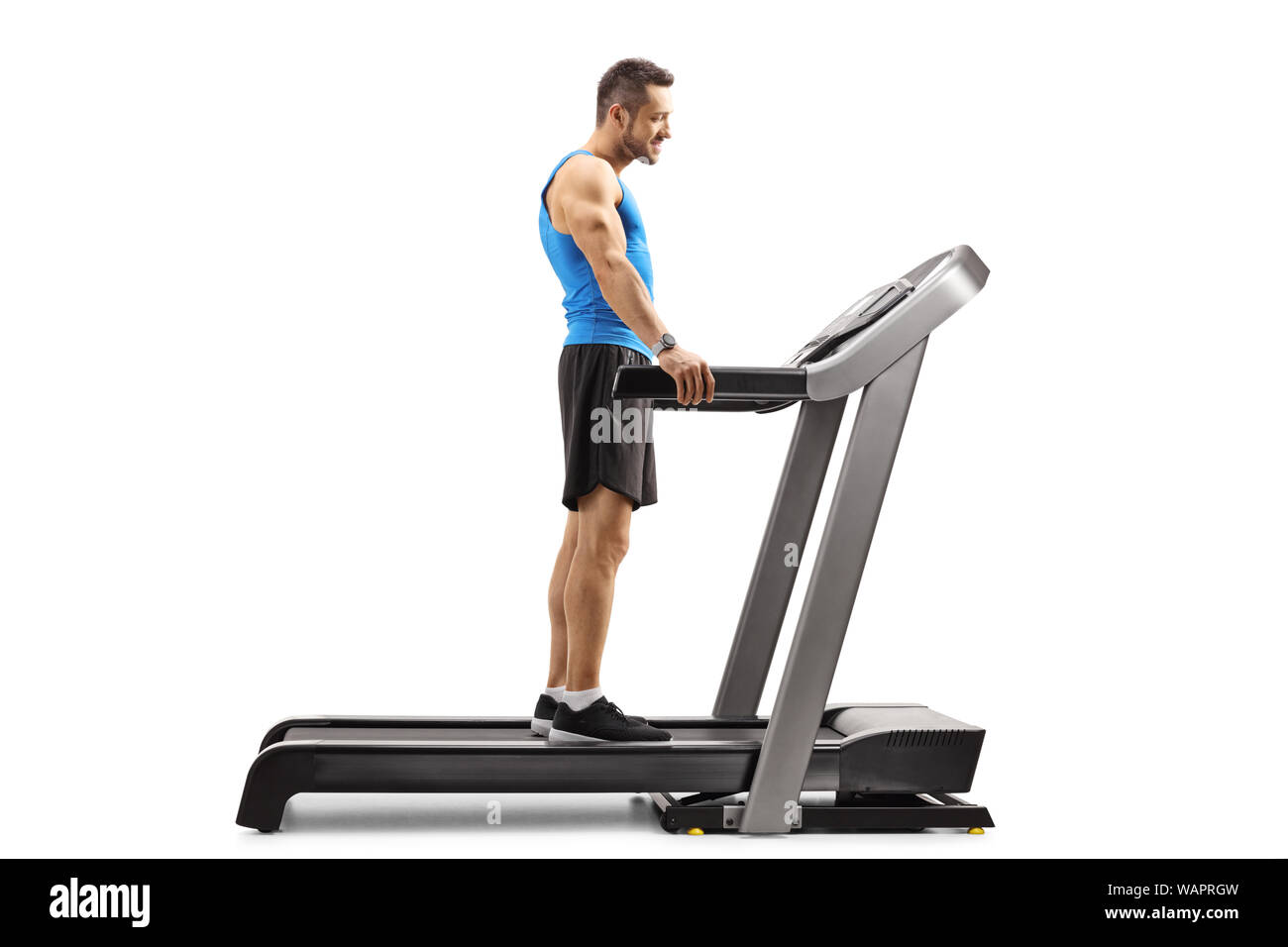 Full length profile shot of a young man standing on a treadmill ...