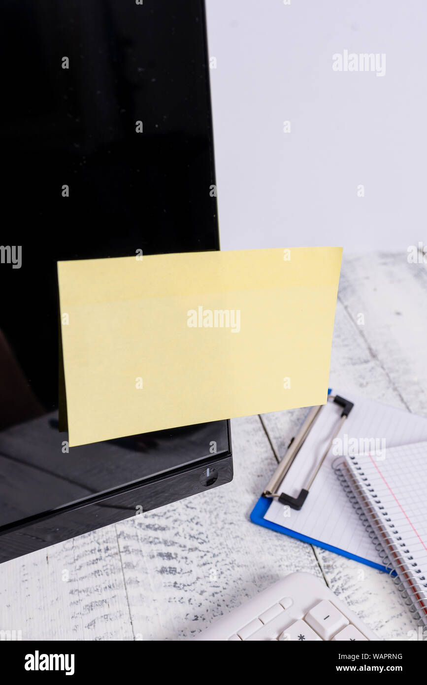 Note paper taped to black computer screen near keyboard and stationary ...