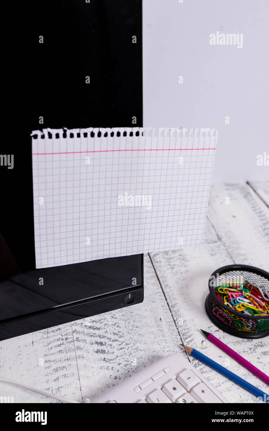 Note paper taped to black computer screen near keyboard and stationary ...