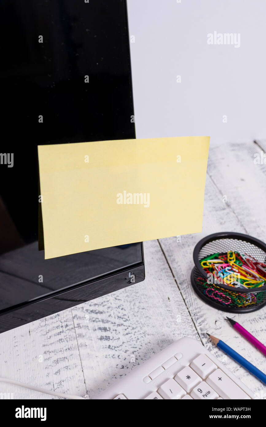 Note paper taped to black computer screen near keyboard and stationary ...