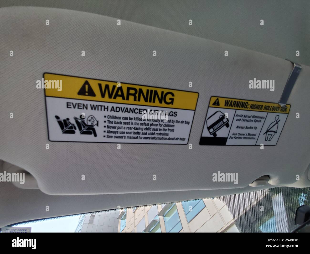 Close-up of warning notice regarding airbag risk on visor of automobile ...