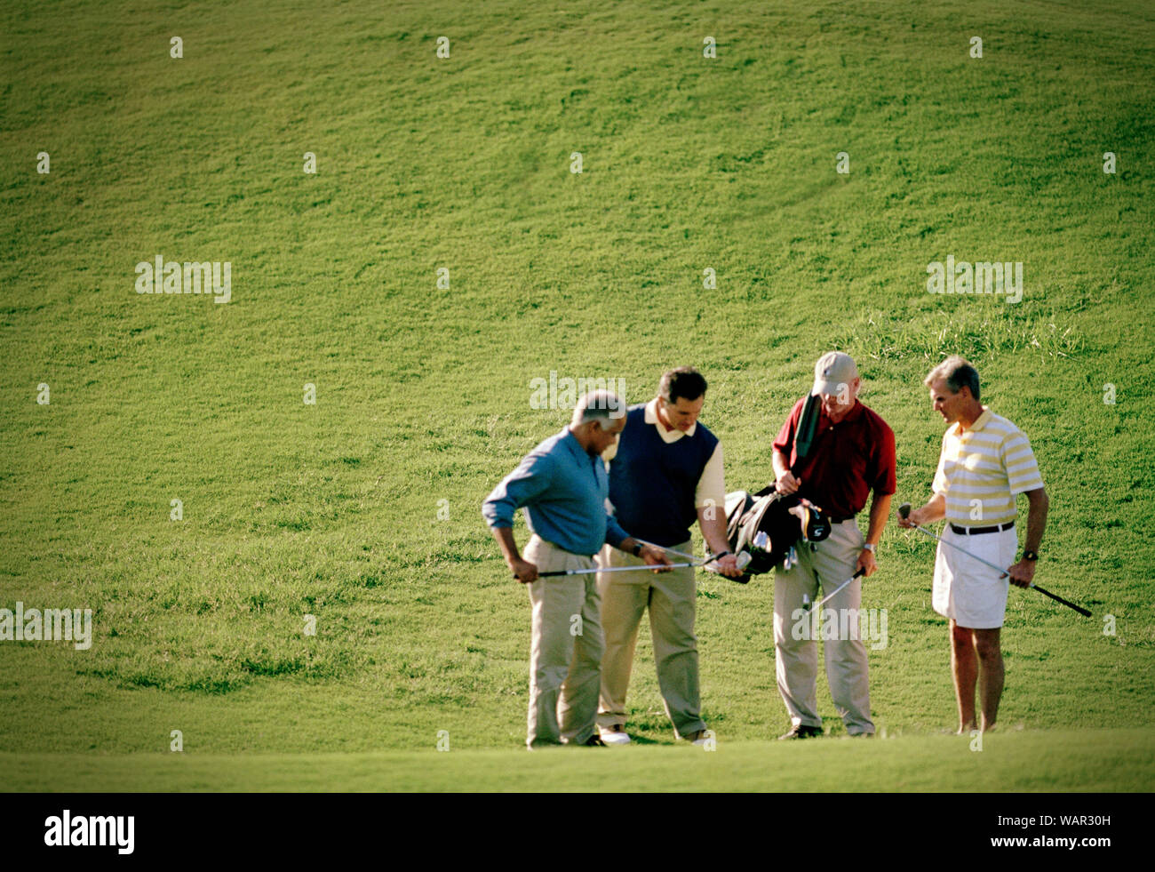 Group of mature men compare their golf clubs on golf course Stock Photo ...
