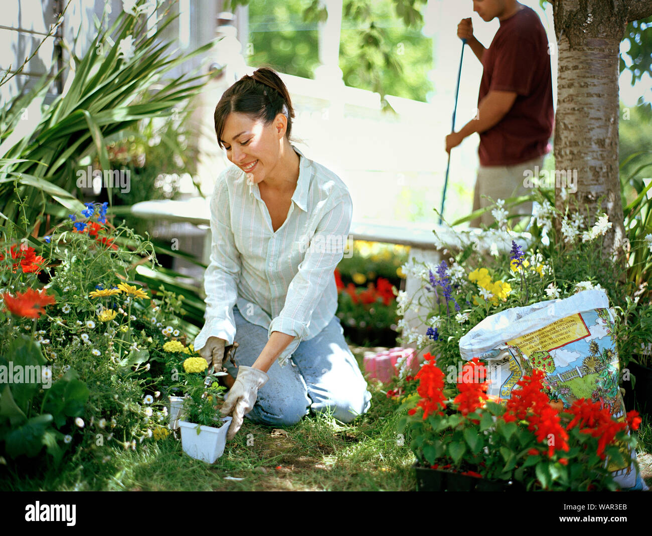 Young woman happily tending to her outdoor garden with her husband ...