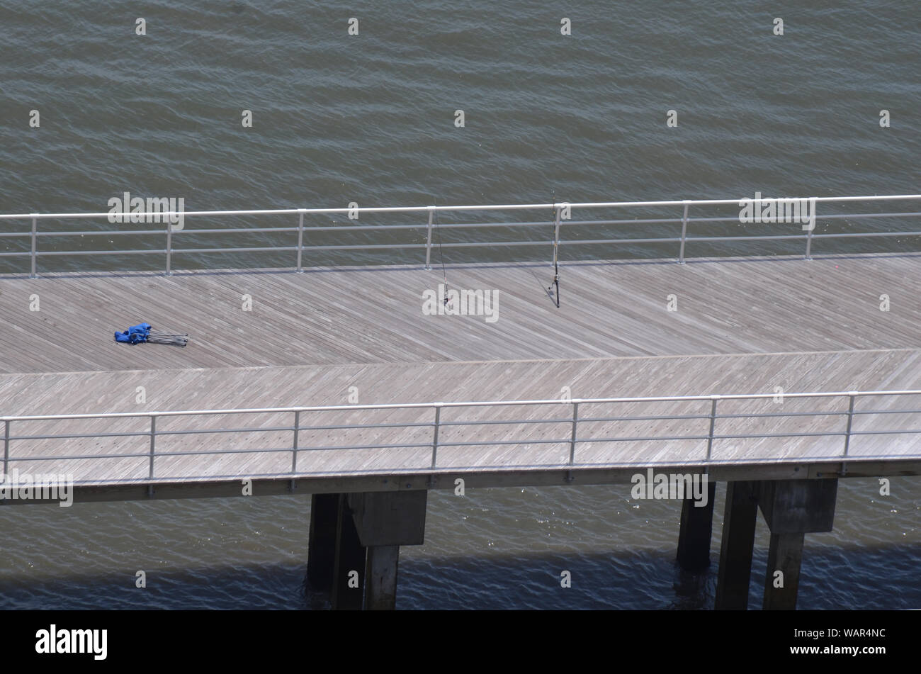 CASTING SEASON: Fishing rods lean on the railing of an empty boardwalk ...