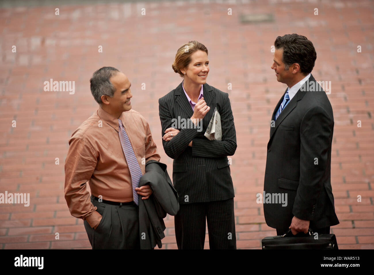 Three business colleagues talking together on a paved sidewalk Stock ...