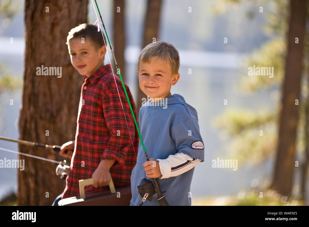 Portrait of two young brothers holding fishing rods while out in the ...