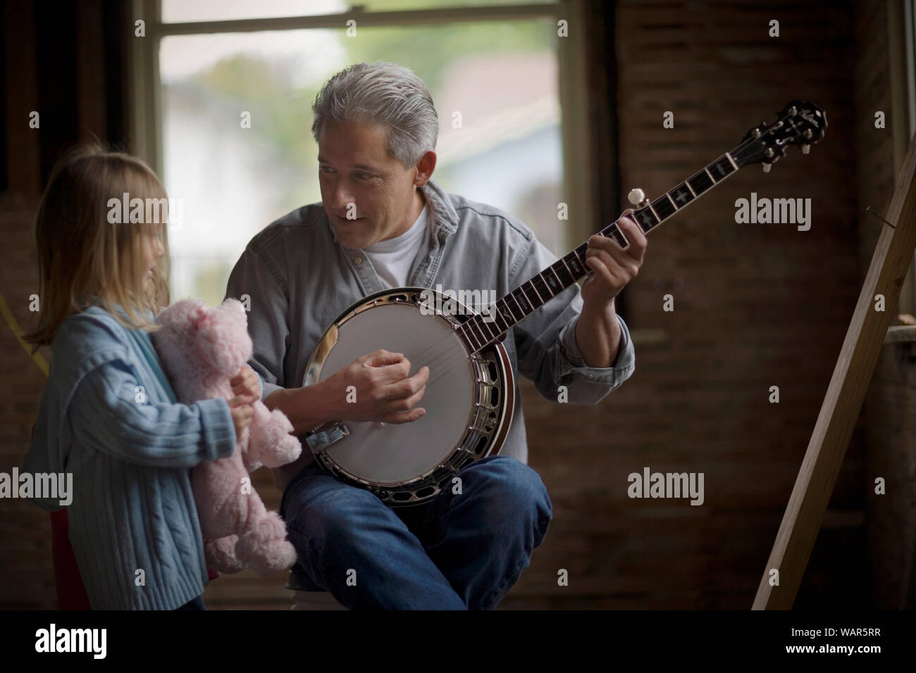 Mid-adult man playing a banjo to his young daughter Stock Photo - Alamy