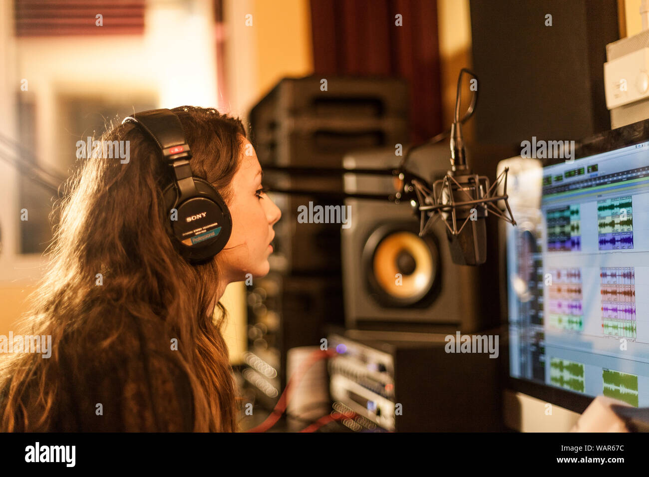 Portrait of a beautiful girl using a condenser microphone in a ...