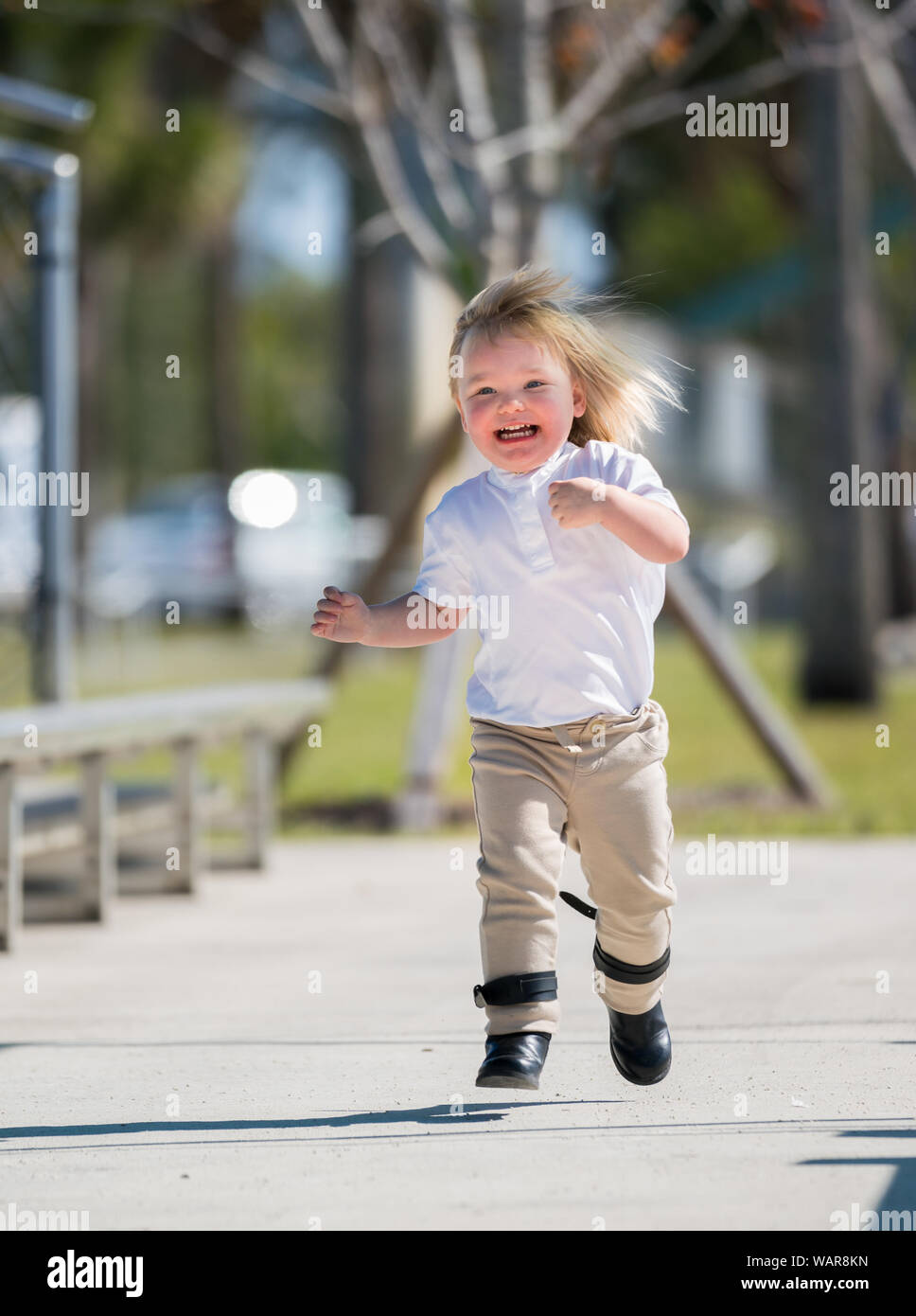 Young child in equestrian clothing is running and smiling Stock Photo ...