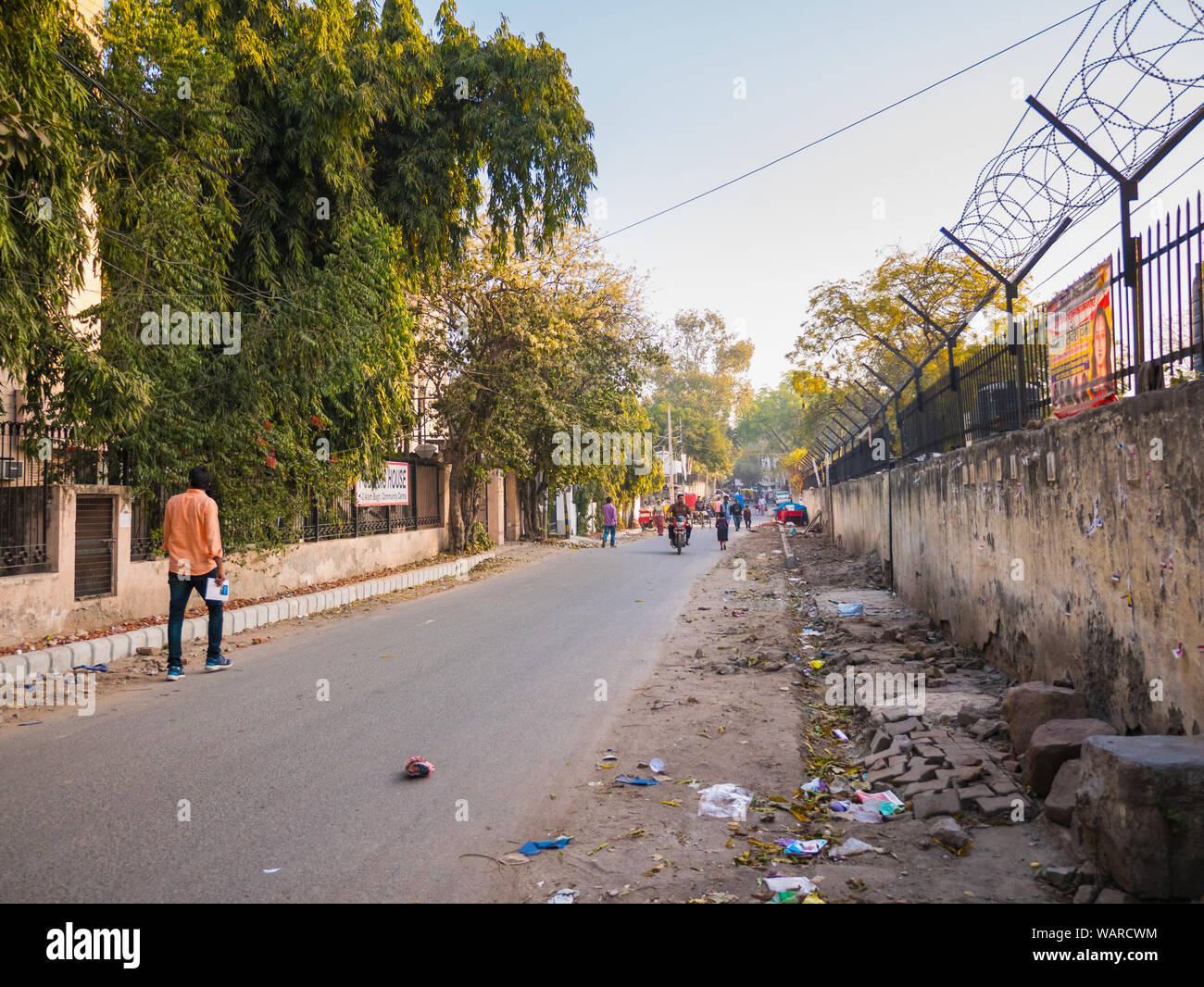 People walking down littered Indian city street in New Delhi, India ...