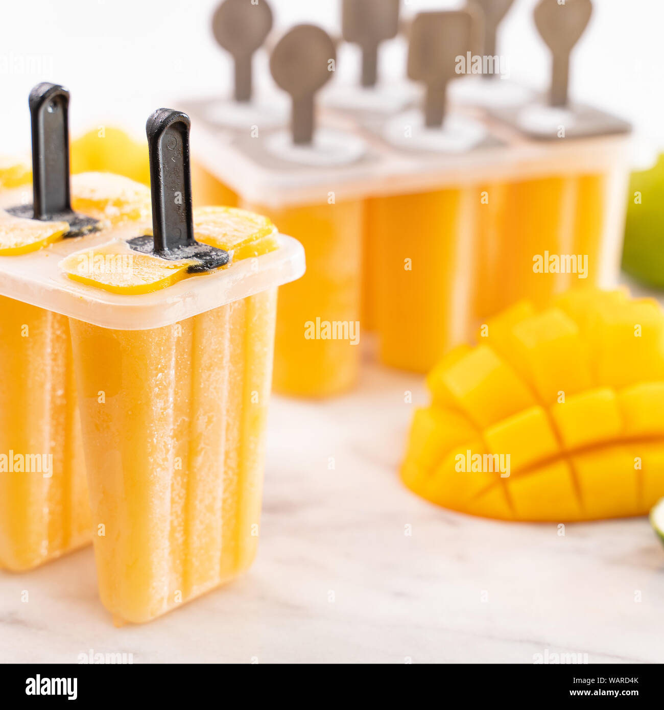 Fresh mango fruit popsicle ice in the plastic shaping box on bright ...