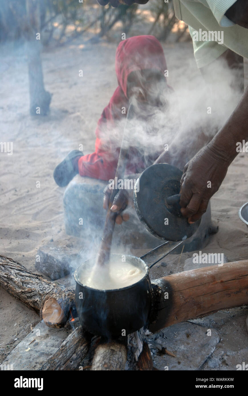 Old lady cooking a pot of Nshima, a thick porridge made from finely ...