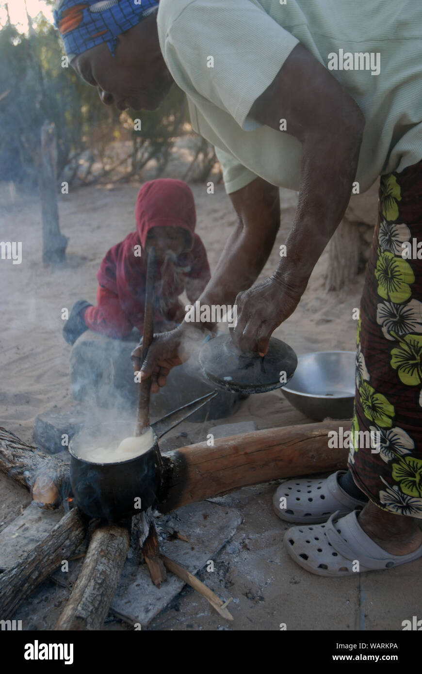 Old lady cooking a pot of Nshima, a thick porridge made from finely ...