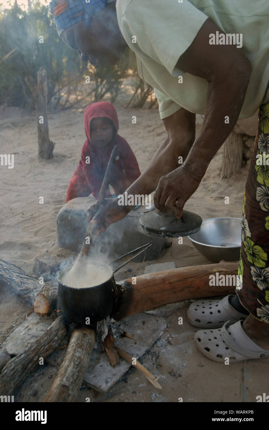 Old lady cooking a pot of Nshima, a thick porridge made from finely ...