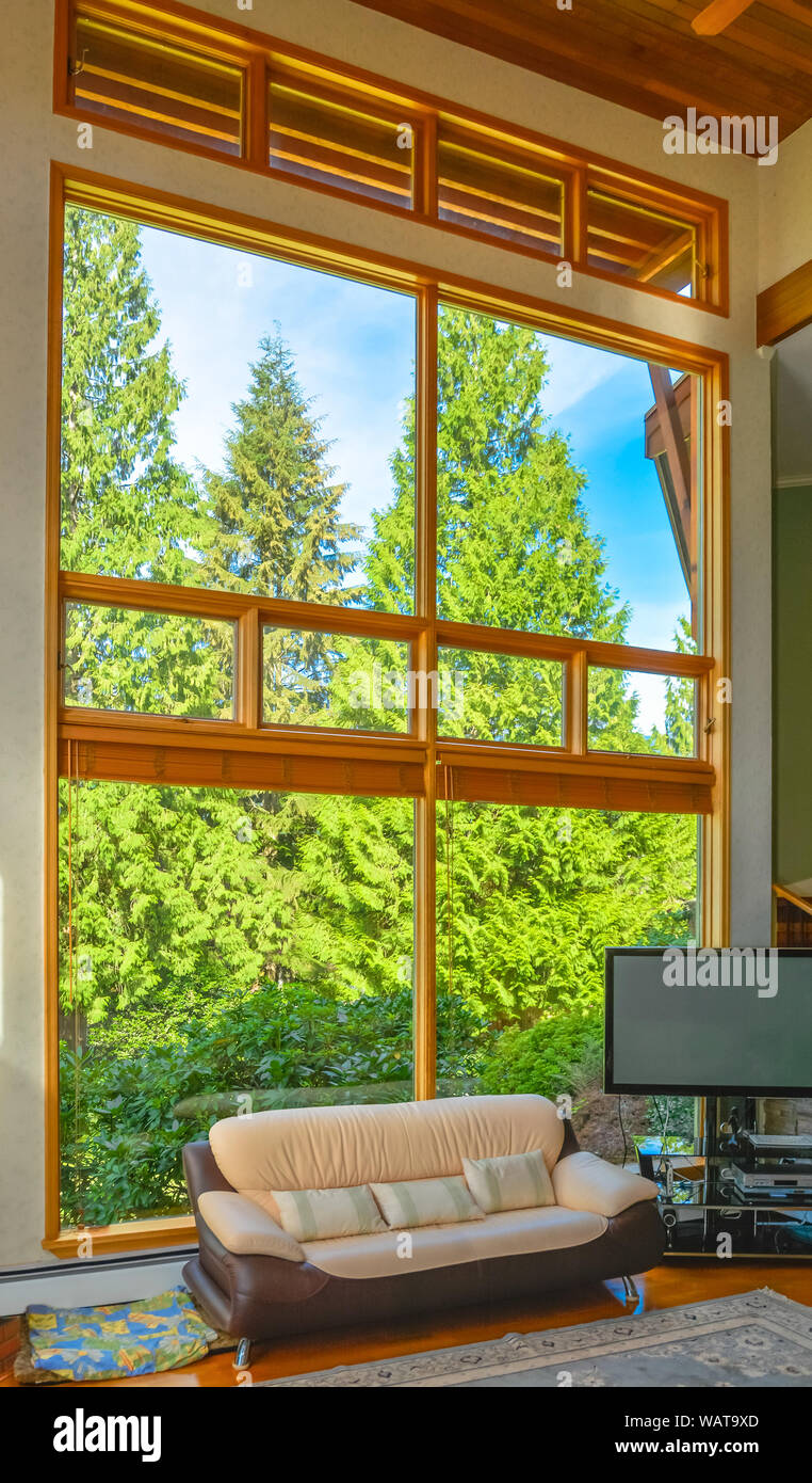 Leather couch and TV set in front of huge window in living room Stock ...