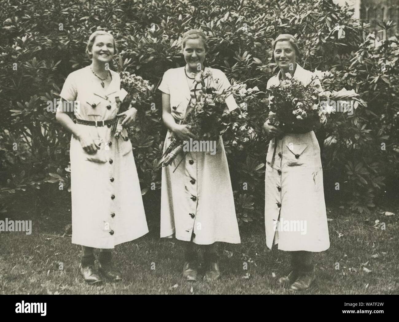Drie deelneemsters met gladiolen aan het einde van de 24e vierdaagse ...