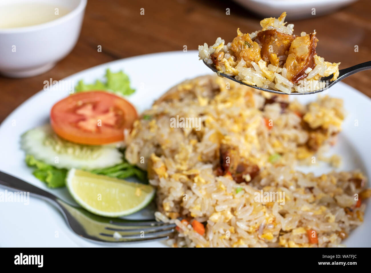 Spoon scooping fried rice with pork and vegetable on dish, Thai cuisine ...