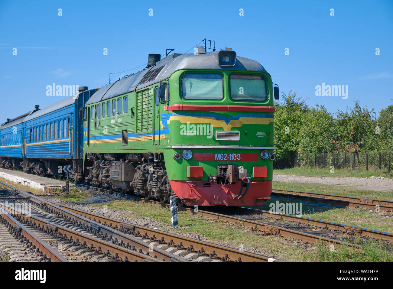 Ukrainian M62 locomotive pulling blue sleeping car wagons at station ...