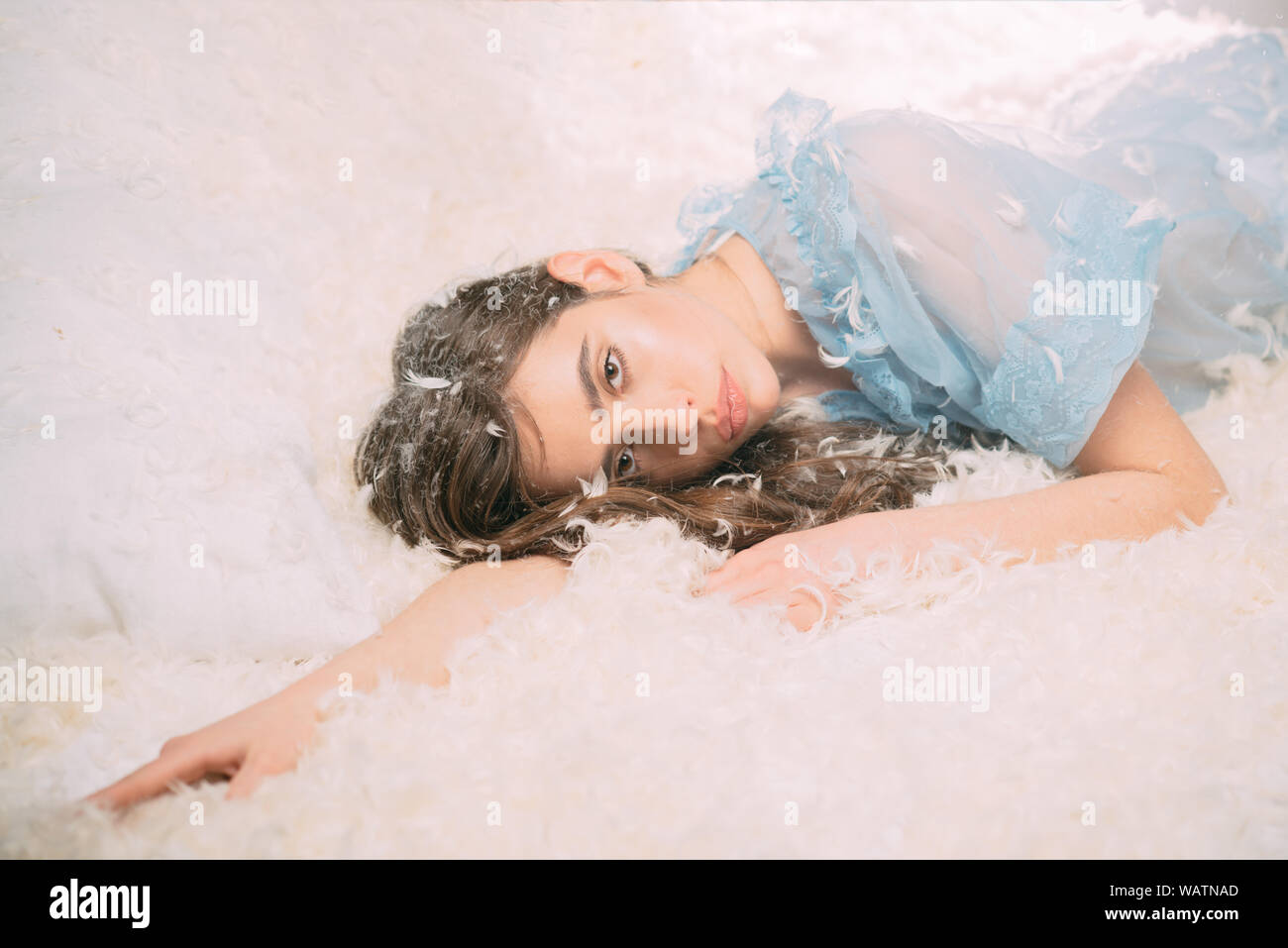 Beautiful brunette teenage girl lying on bed after pillow fight, tiny ...