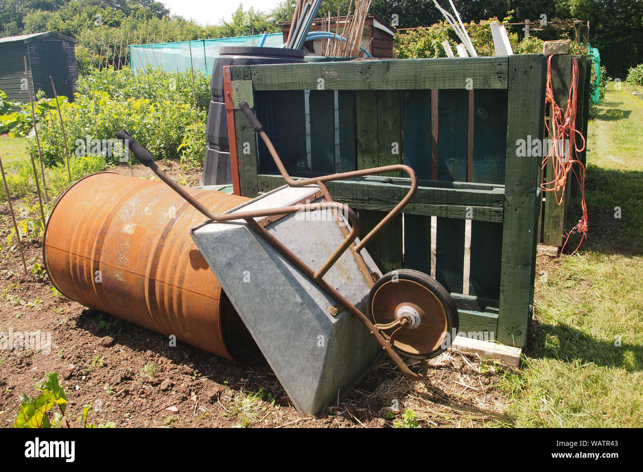 An upturned wheelbarrow leaning on a barrel converted to an incinerator ...
