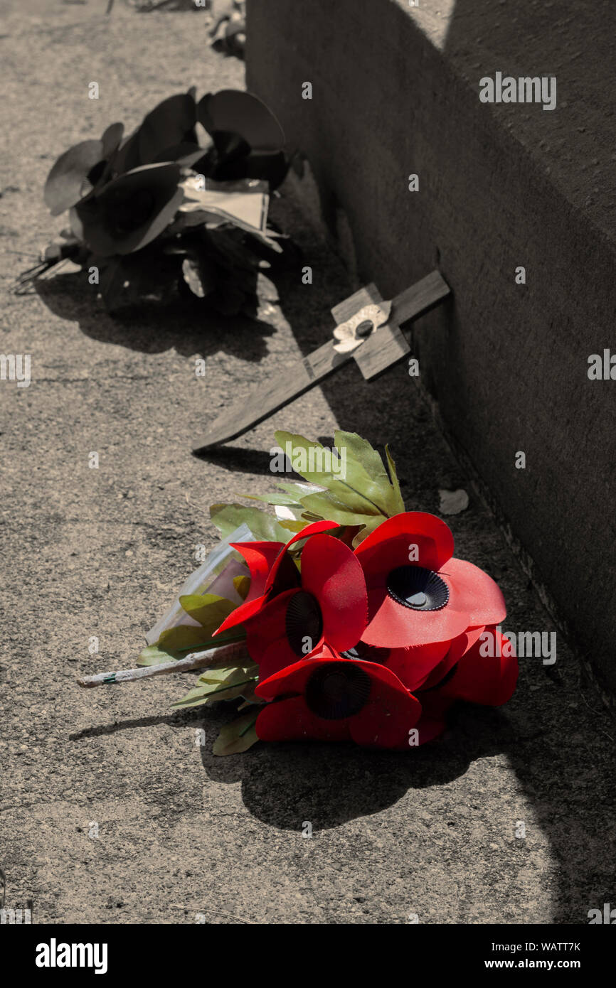 Poppy wreath, with selective colour, on the base of a war memorial ...