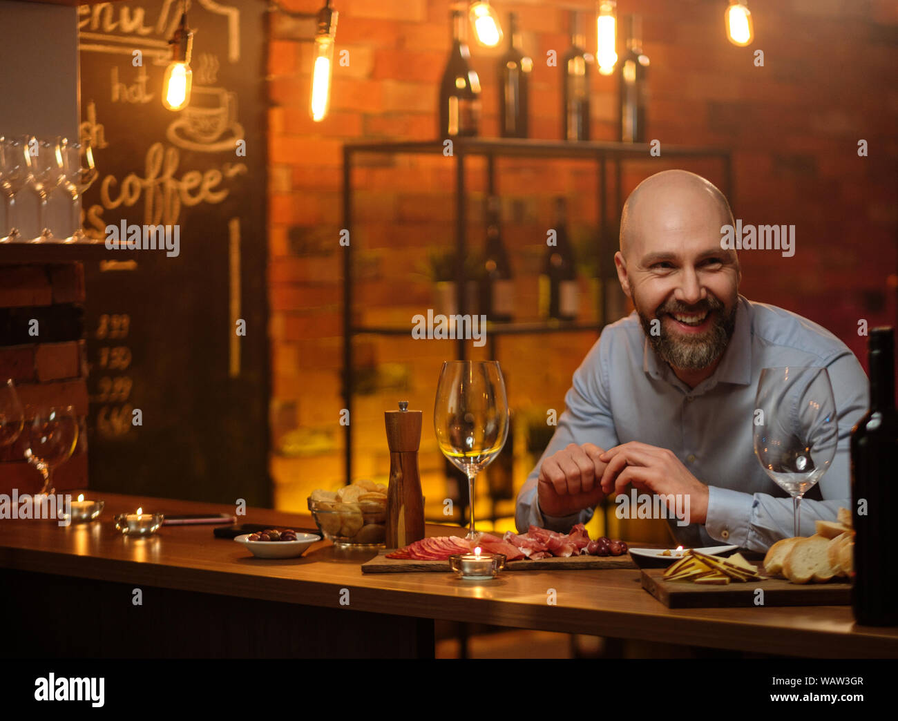 Middle-aged man sitting behind bar counter Stock Photo - Alamy