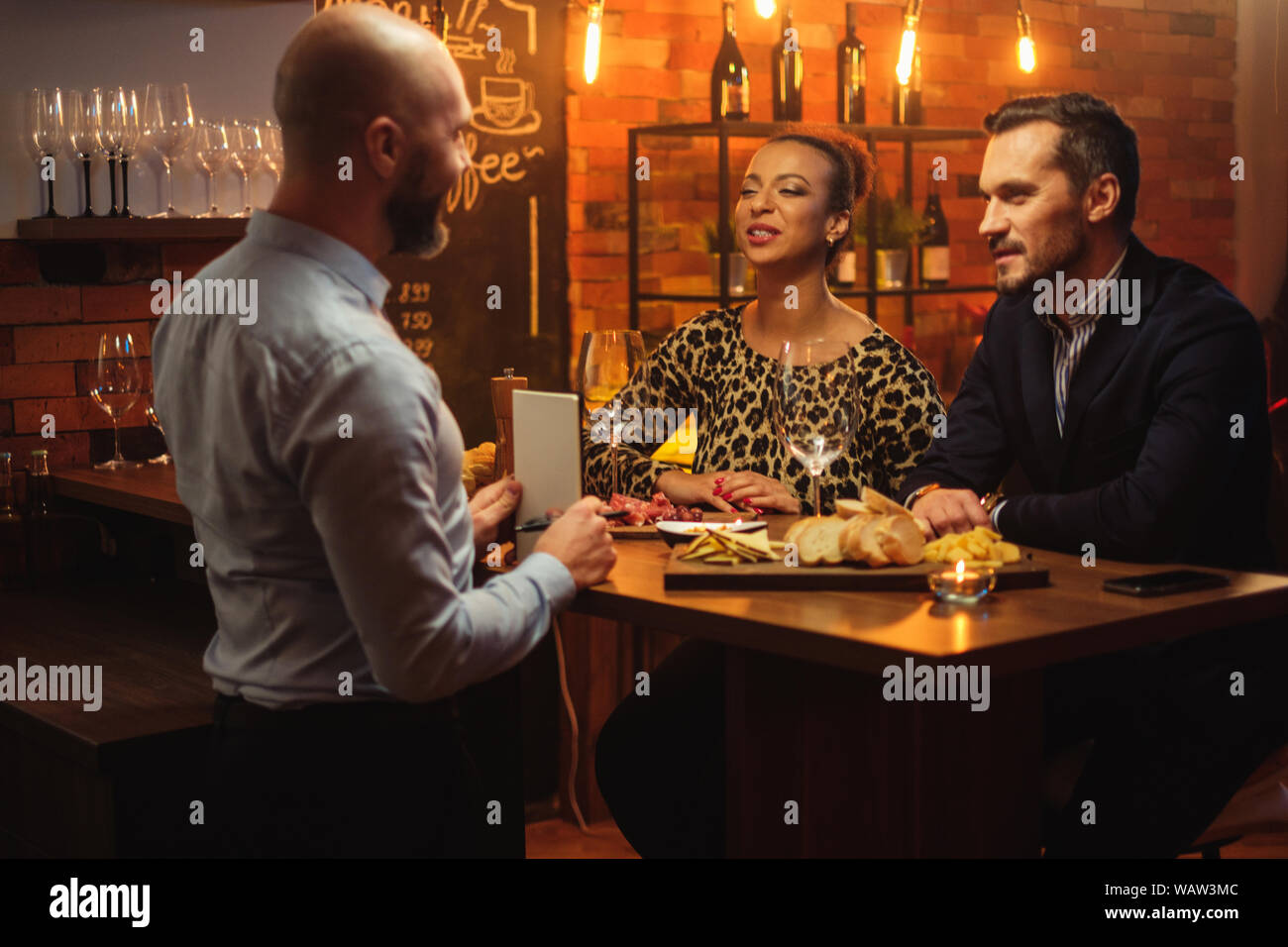 Couple talking to bartender behind bar counter in a cafe Stock Photo ...