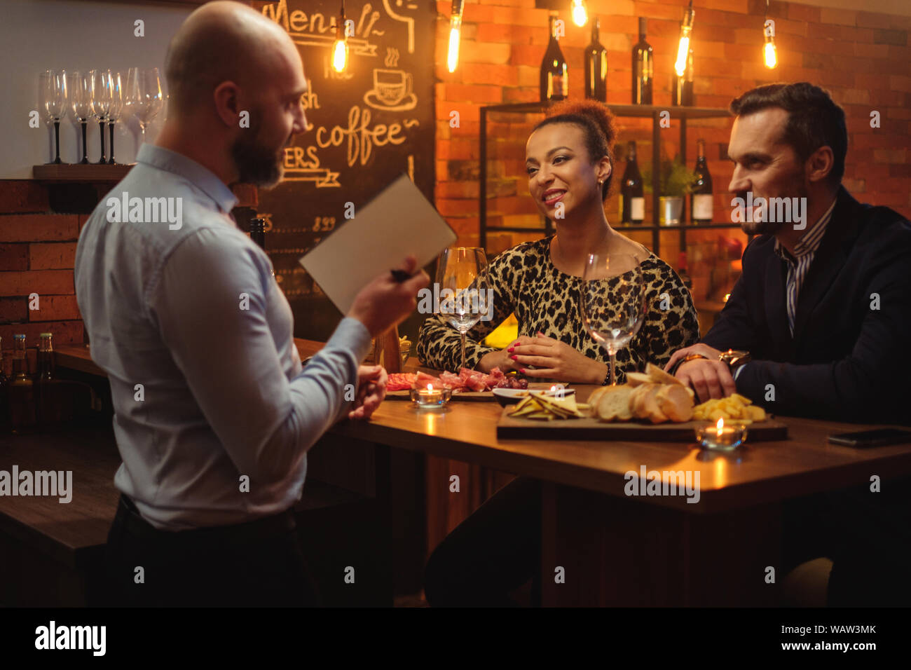 Couple talking to bartender behind bar counter in a cafe Stock Photo ...
