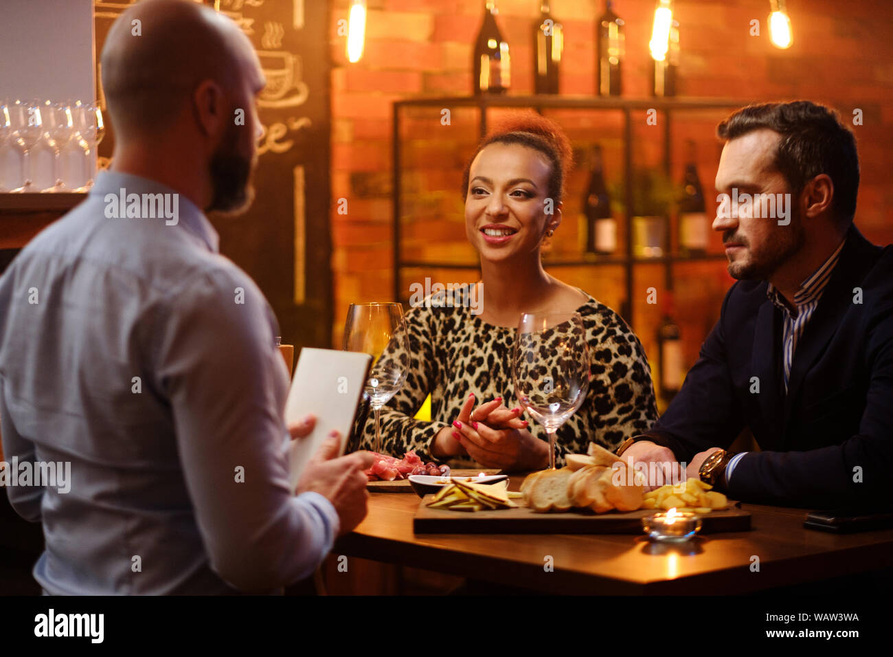 Couple talking to bartender behind bar counter in a cafe Stock Photo ...