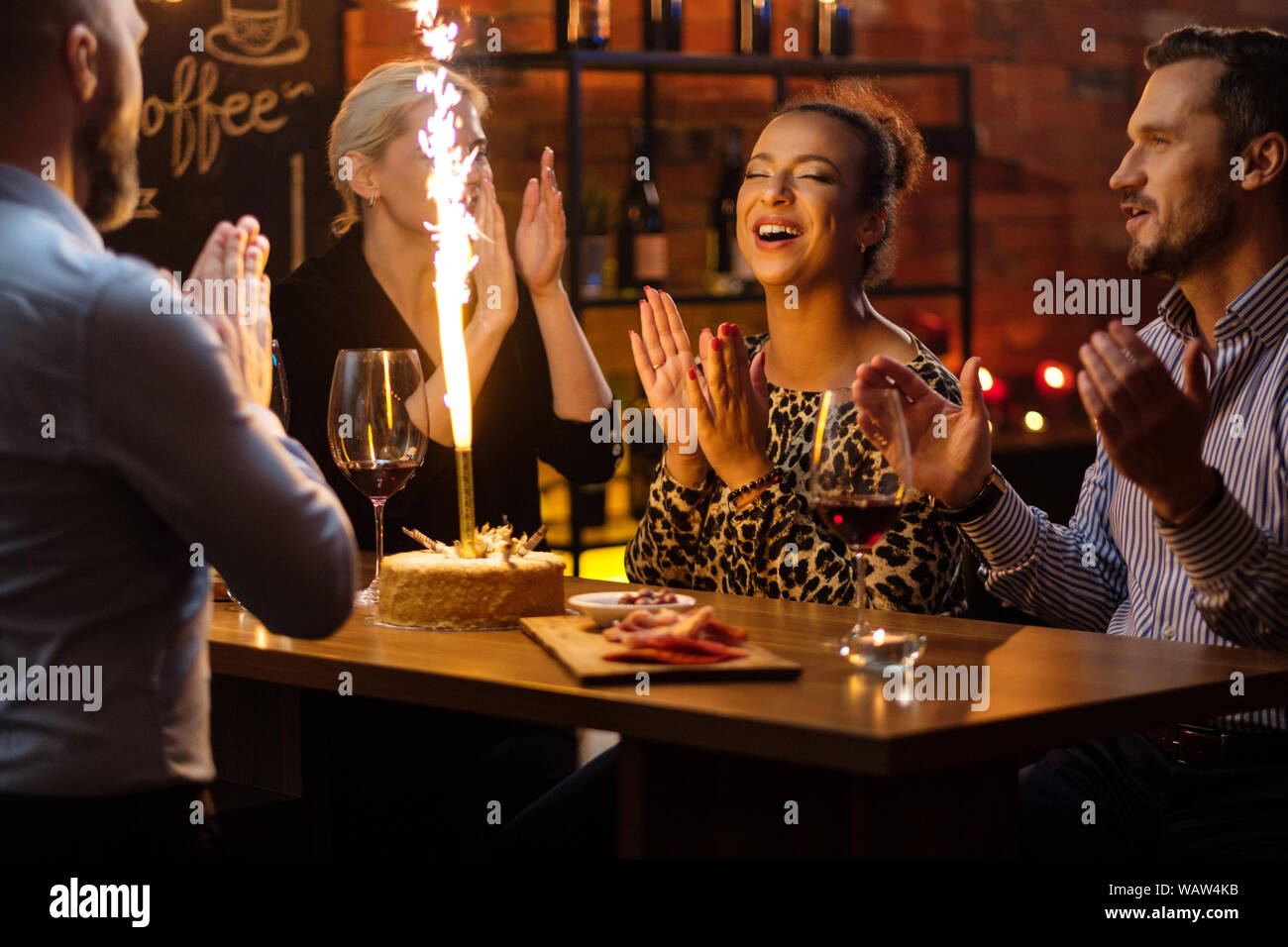 Group of friends celebrating birthday in a cafe behind bar counter ...