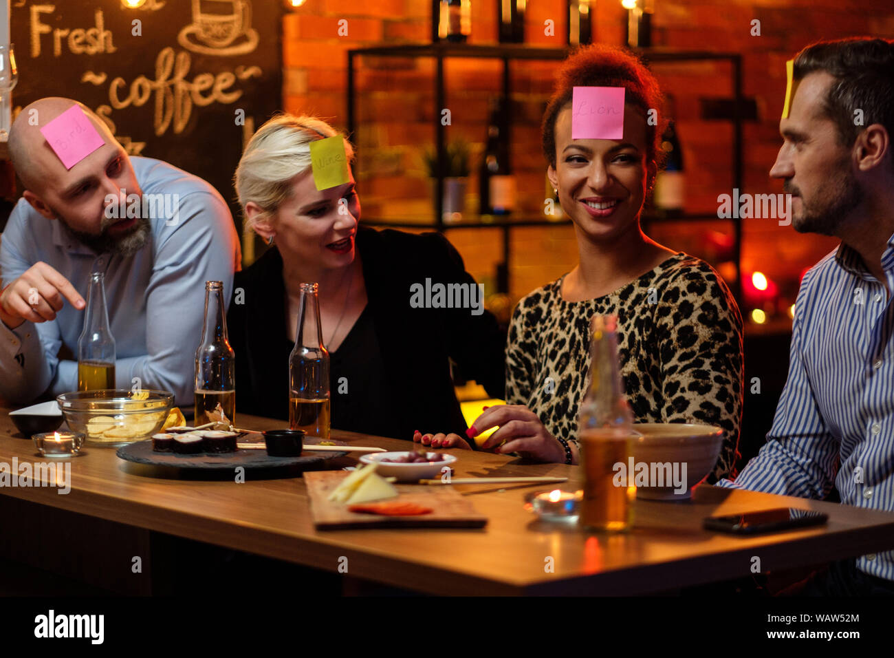 Group of friends playing sticky head game behind bar counter in a cafe ...