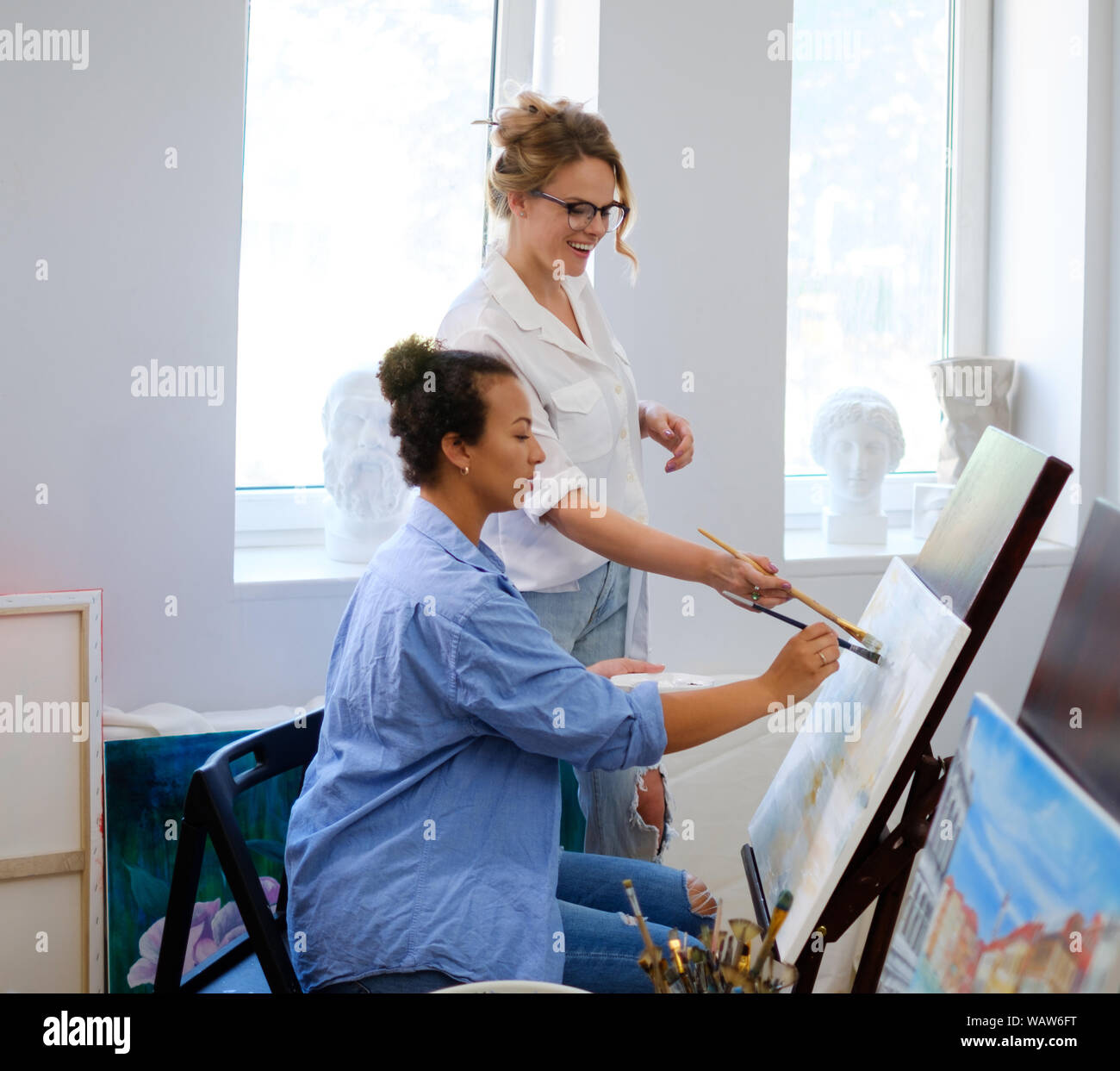 Creative painter and her protege working in a studio Stock Photo - Alamy